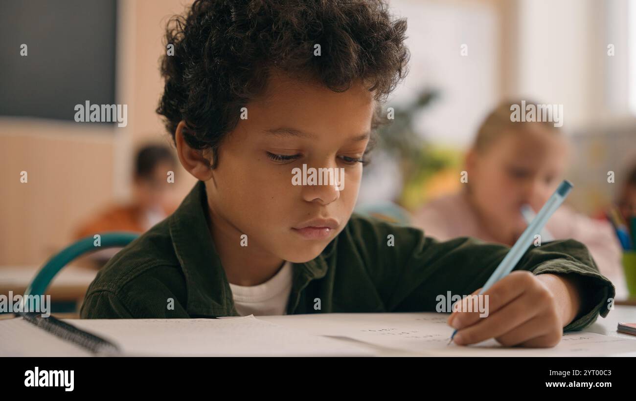 Little African American guy boy writing notes task class lesson primary ...