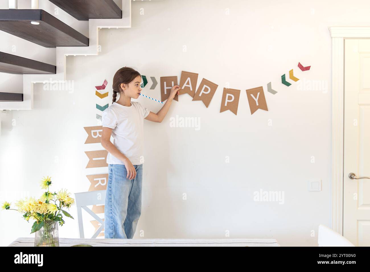 Preparation for the birthday. Girl hangs Happy Birthday sign on a wall ...