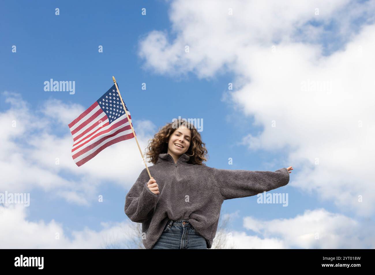 adult teenage girl stands against a background of blue sky with an ...