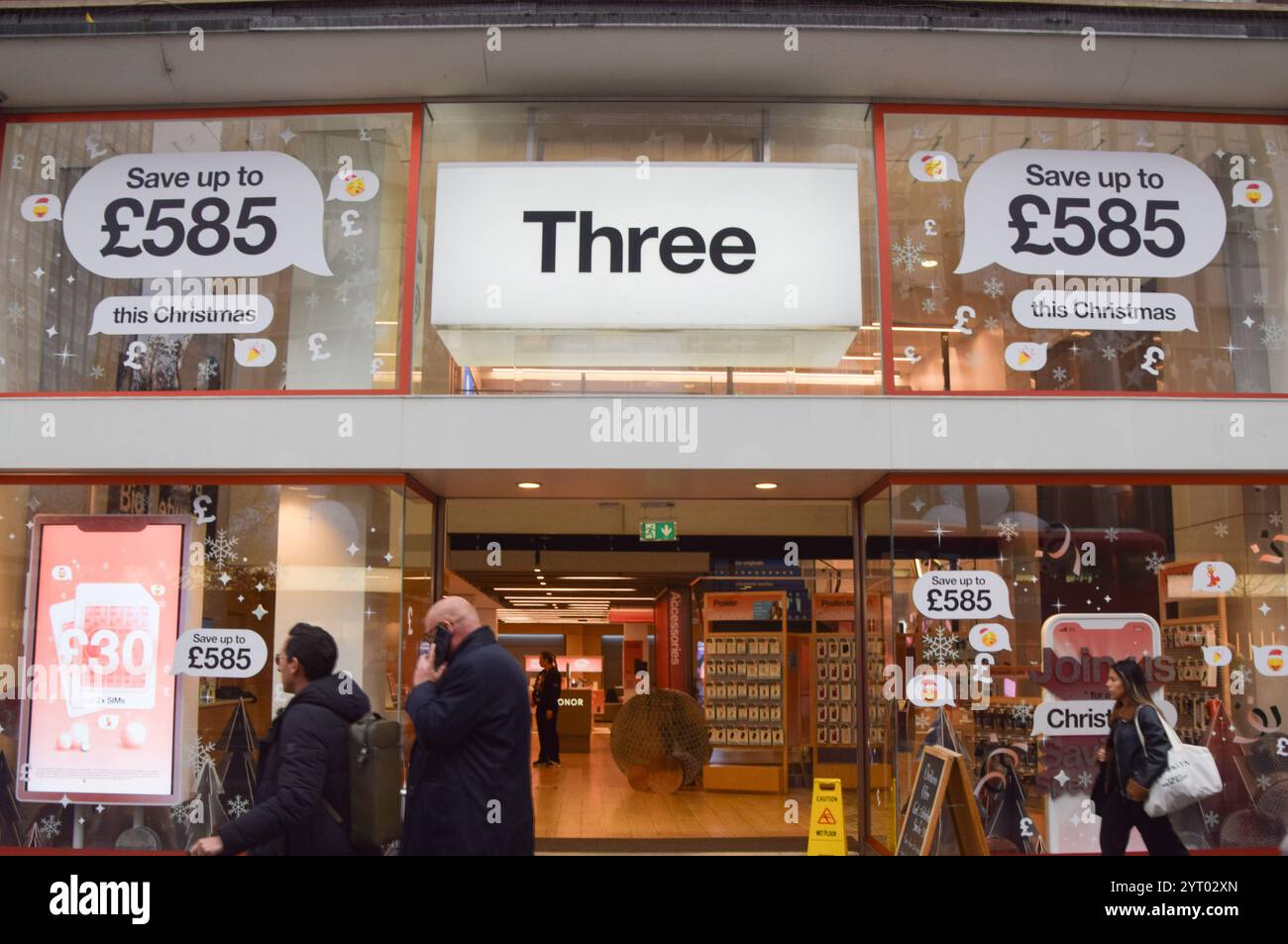 London, UK. 5th December 2024. People walk past a Three mobile phone ...