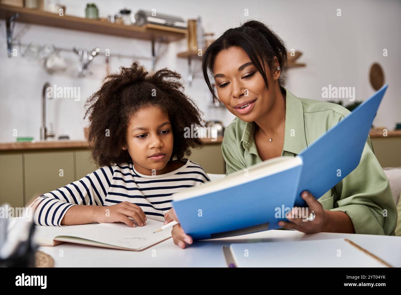 A mother and daughter share a joyful reading session at home, bonding ...