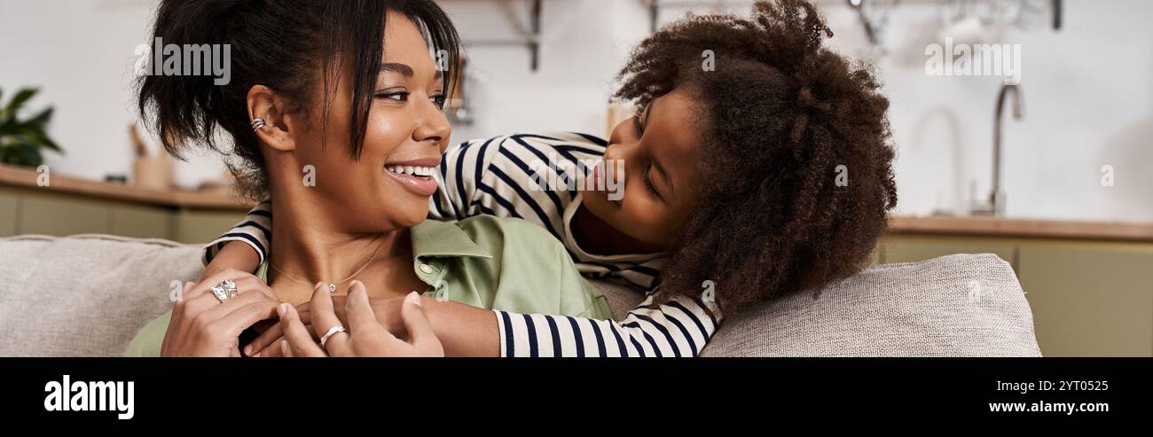 A mother smiles lovingly as her daughter playfully embraces her from ...