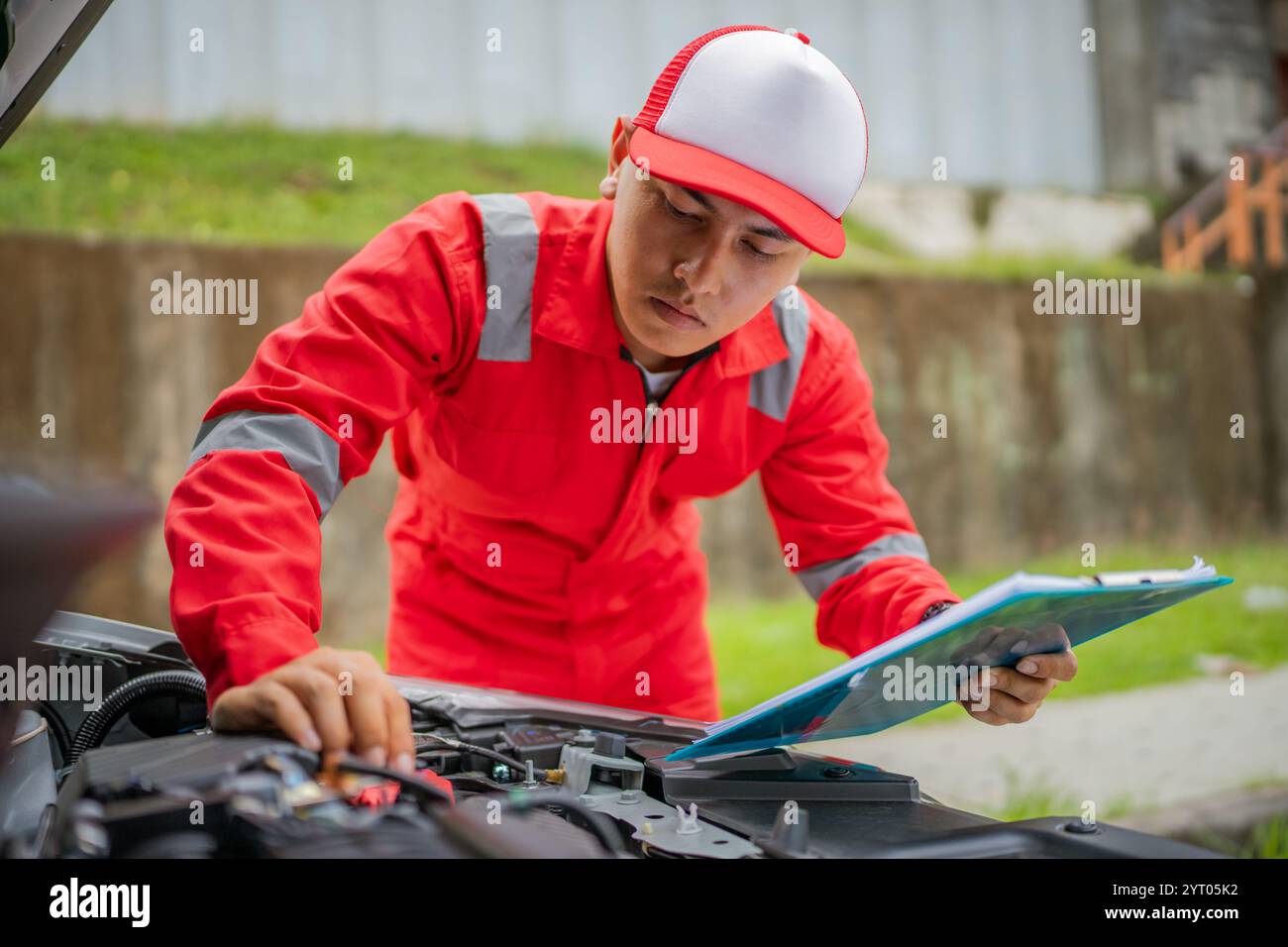 Automotive Technician Diagnosing Complex Engine Issues in a Red Uniform ...