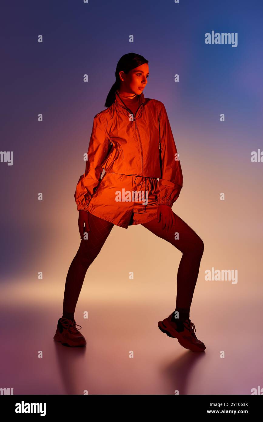 A chic young woman models her fashionable outfit in a dramatic studio ...