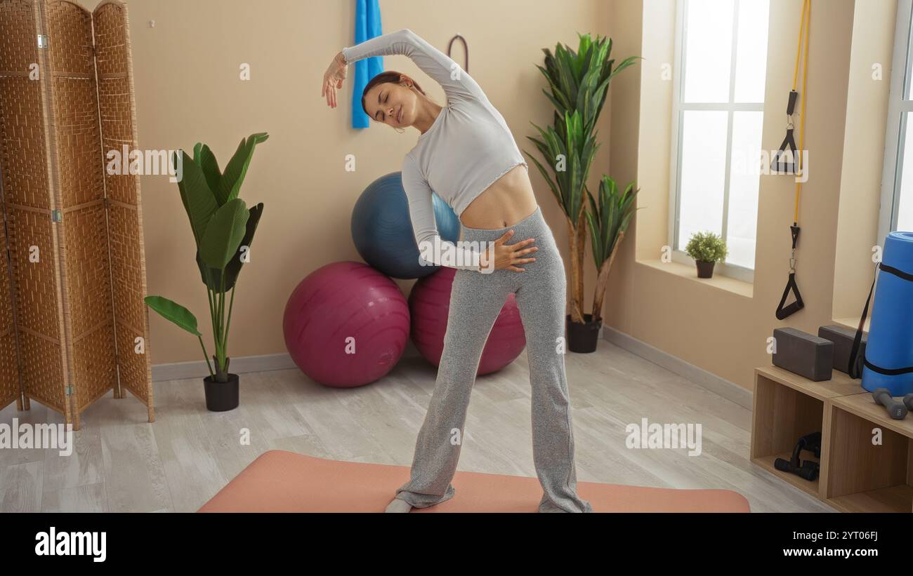 Woman stretching in gym with yoga mat exercise ball plants exercise ...