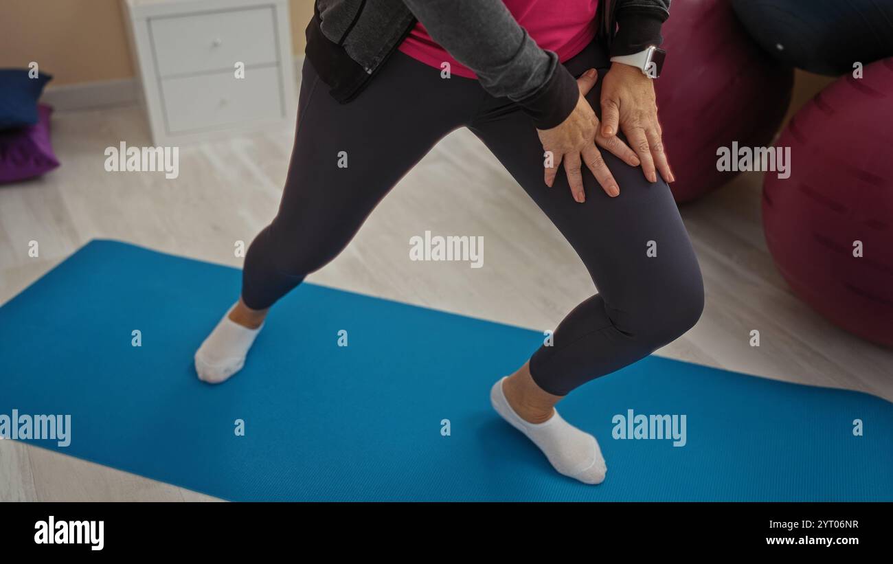 Woman exercising on yoga mat indoors with knees bent and hands on ...