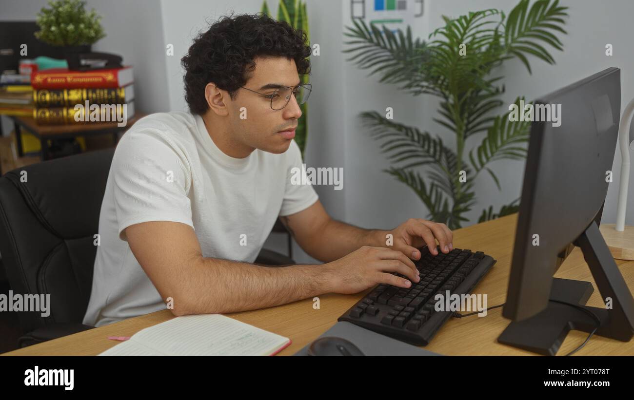 A young hispanic man working diligently on a computer in an office ...