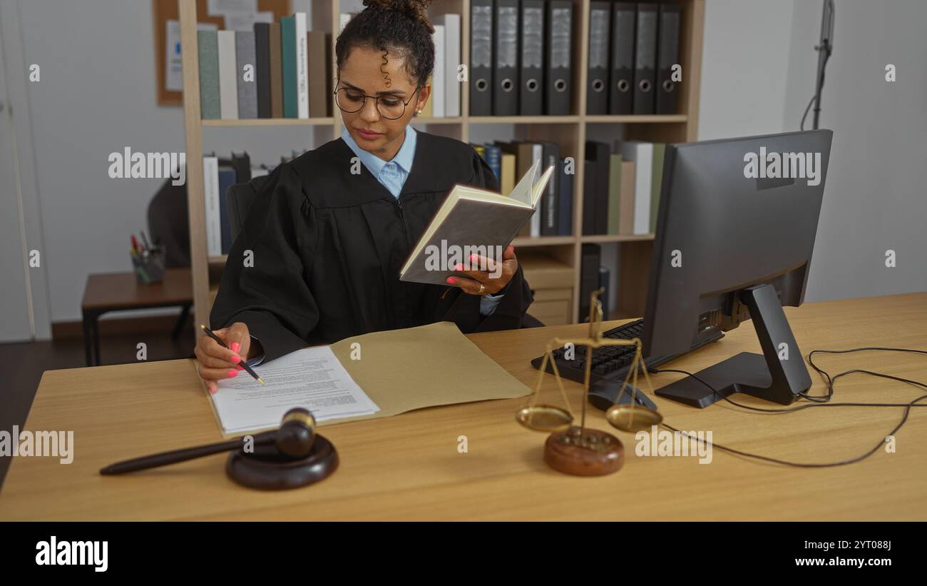 Hispanic woman judge reviewing documents and reading a book at her desk ...