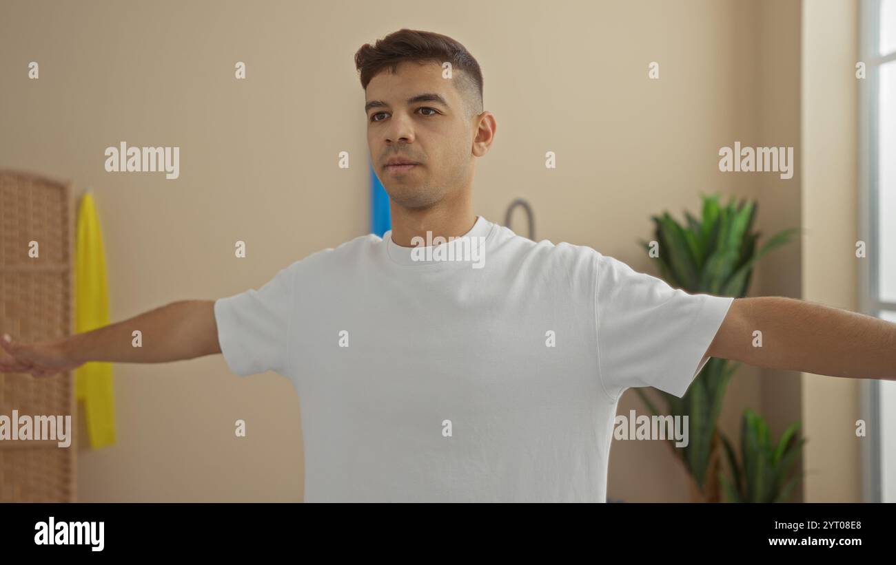 Young man exercising indoors at gym stretches arms wearing white shirt ...