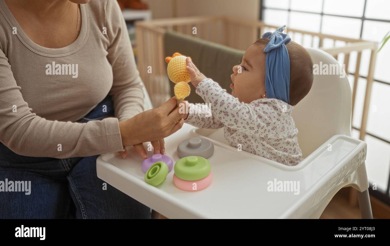 Woman interacting with baby in bedroom setting with toys on highchair ...