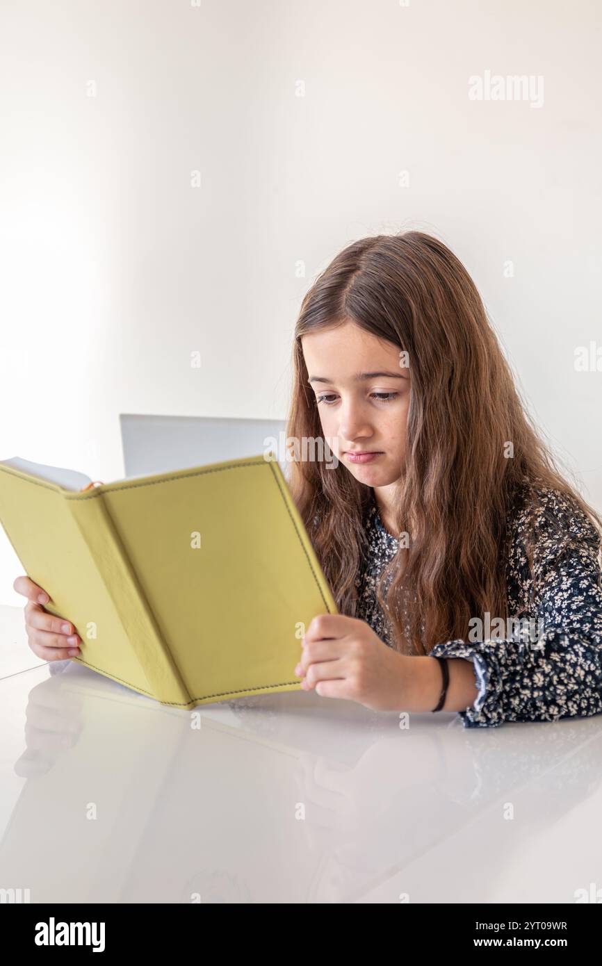 Sad girl reading a book at home. Girl student teaches lessons to school ...