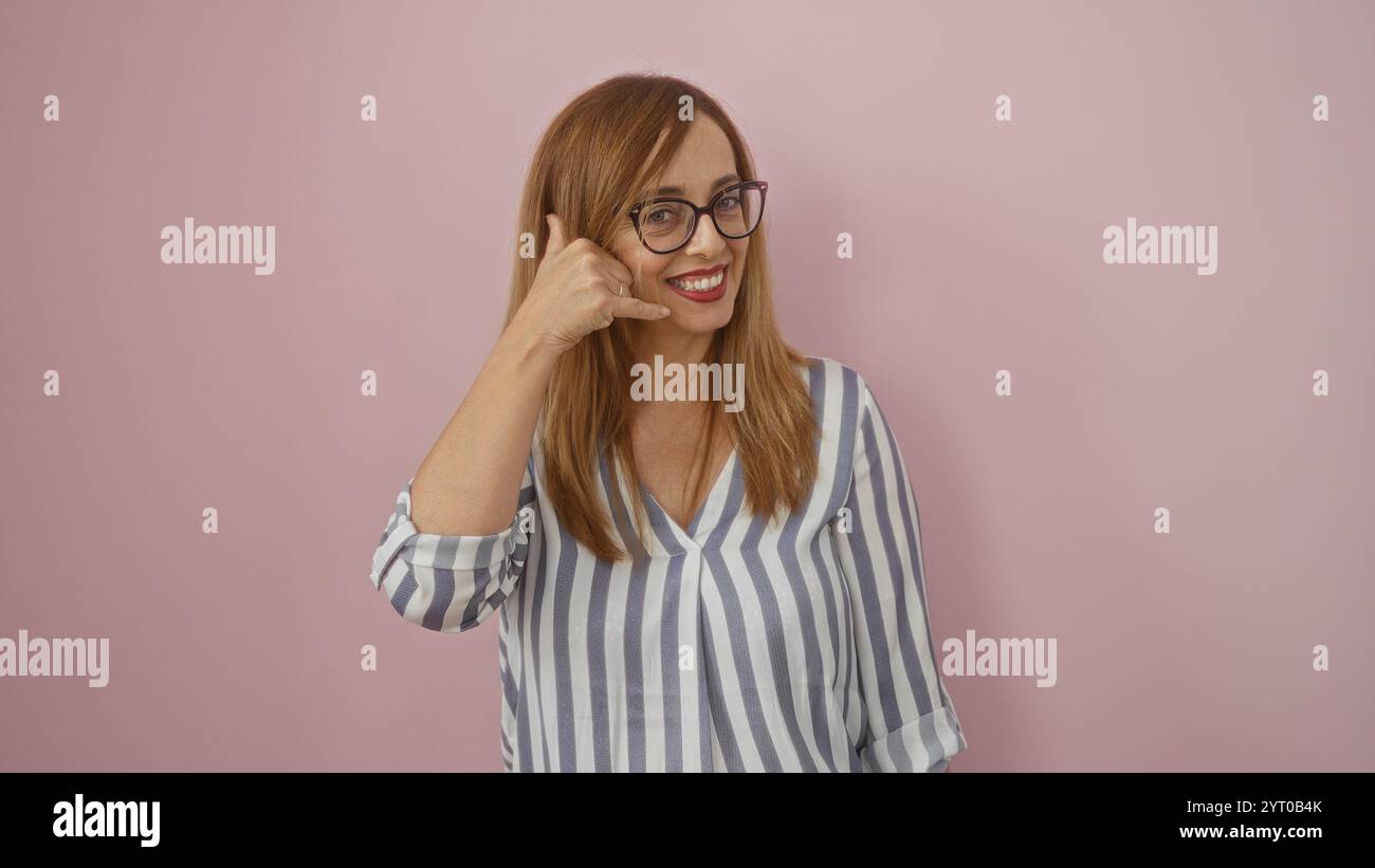 Woman smiling wearing glasses making call me gesture against pink ...
