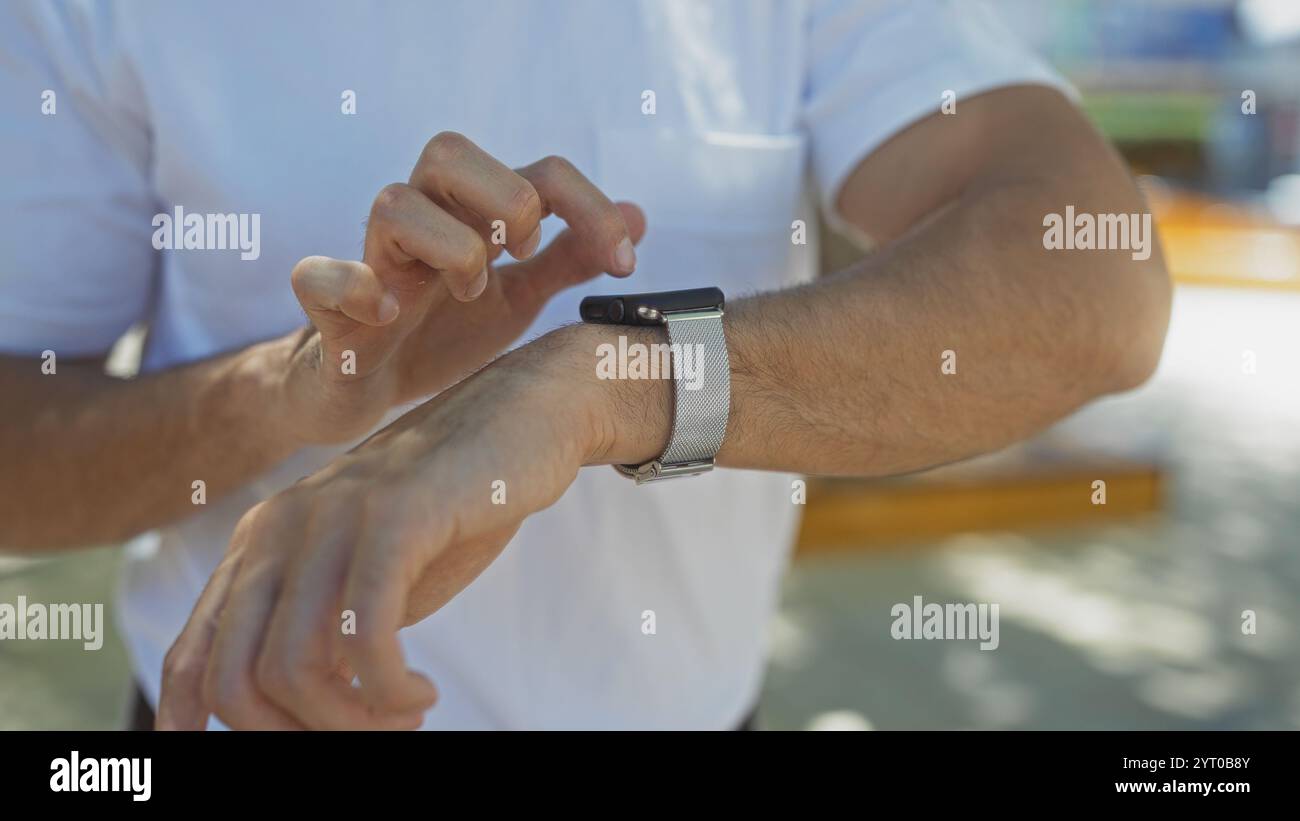 Hispanic man using smartwatch in urban park setting, illustrating hands ...