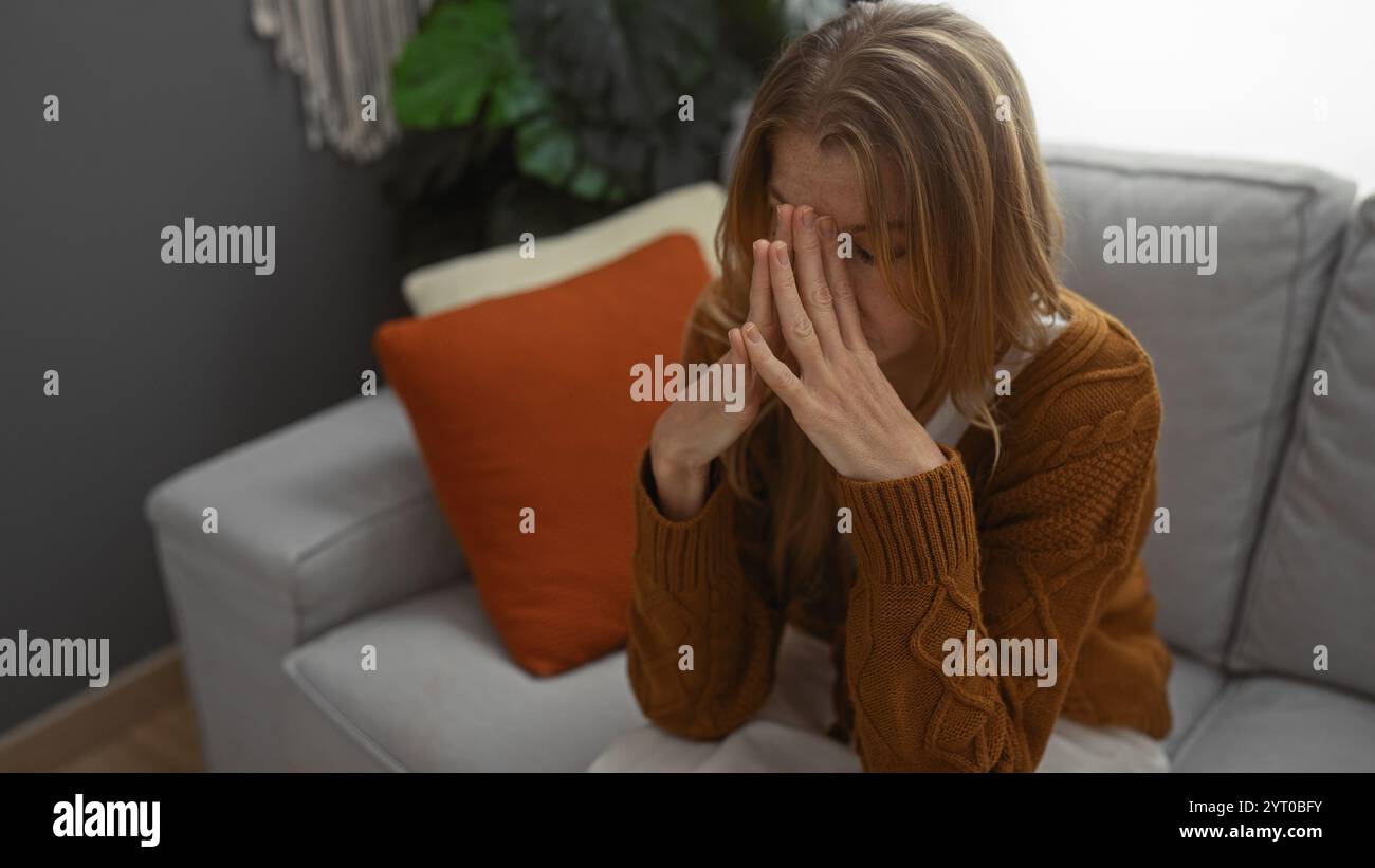 Woman sitting on a comfortable couch in a living room with hands ...