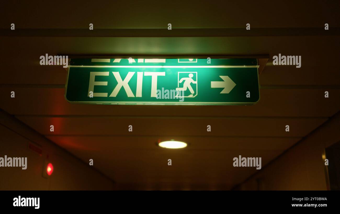 Illuminated exit sign glowing indoors shows direction in a dimly lit ...