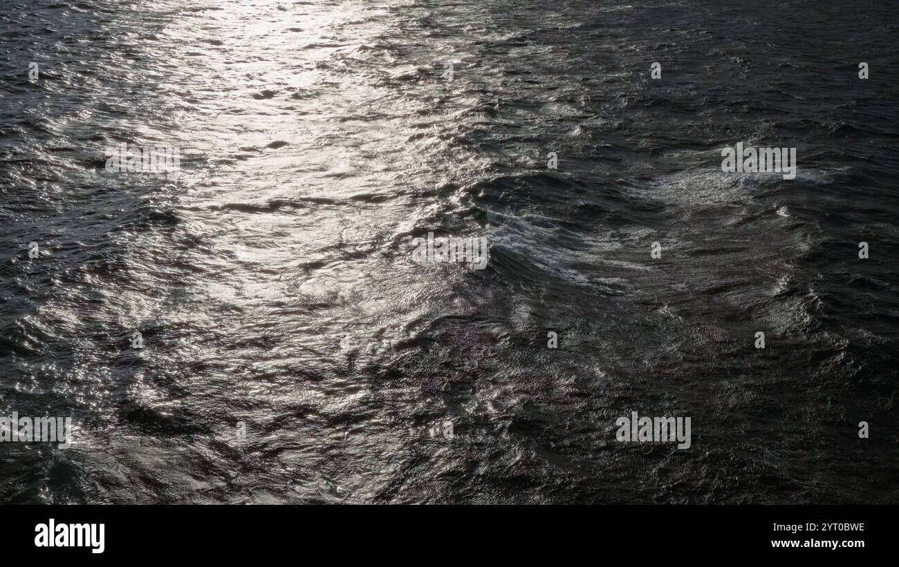 Sunlight glistens on the rippling ocean waves creating a serene and ...