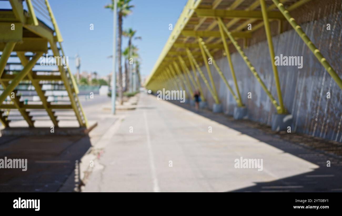 Blurry outdoor urban scene with defocused pedestrian bridge, palm trees ...