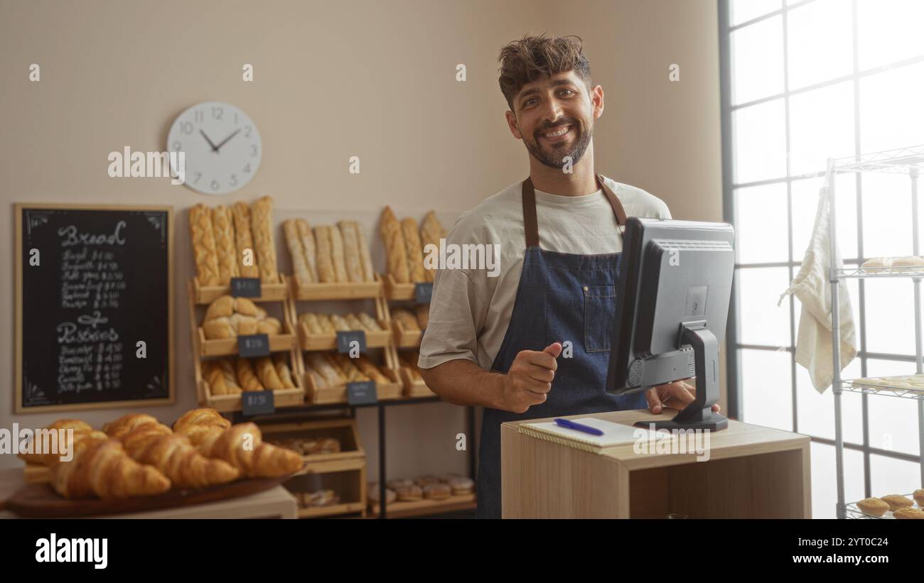 Handsome man smiling in a bakery shop interior with fresh bread and ...