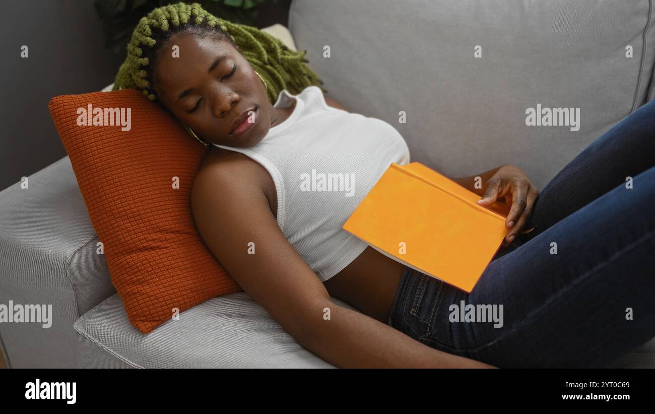 Woman sleeping on sofa with book on her stomach, in a cozy living room ...