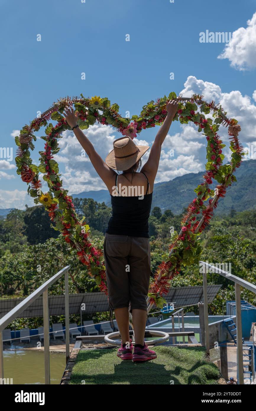 Woman looks at the landscape through a heart-shaped structure decorated ...