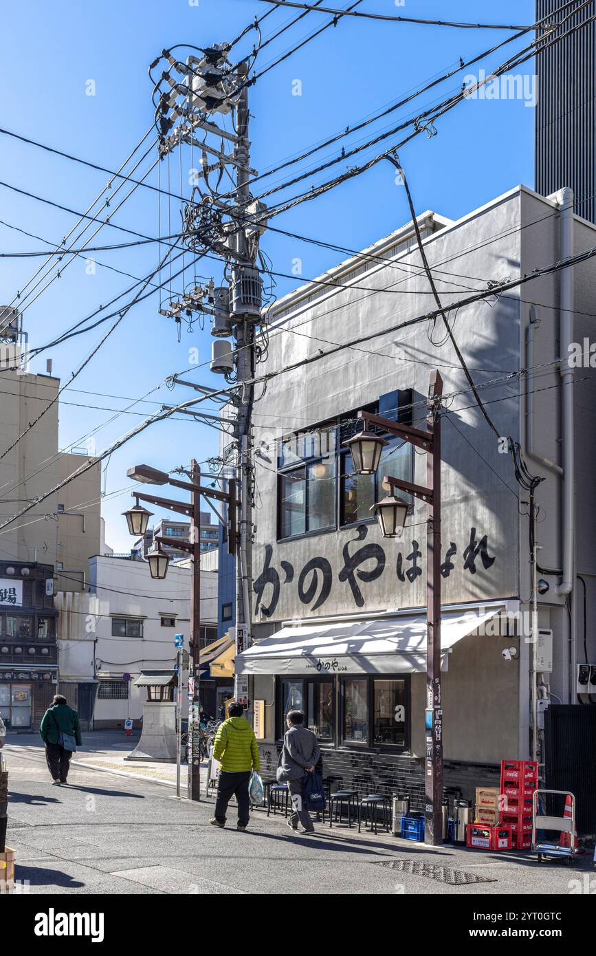People walking on a typical japanese street with messy power lines and ...