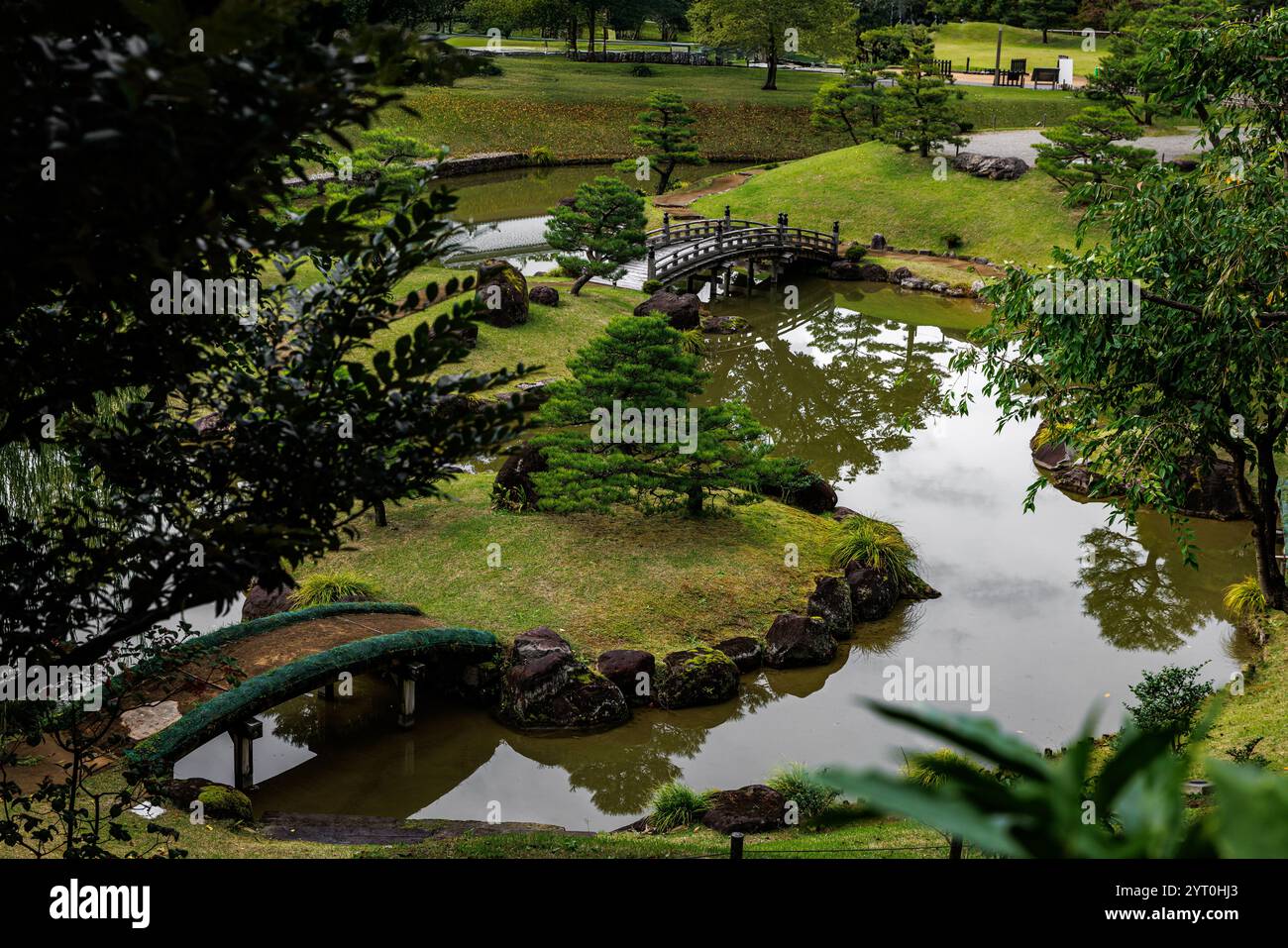 A tranquil garden with scenic ponds, lush greenery, and charming footbridges that embody natures ...