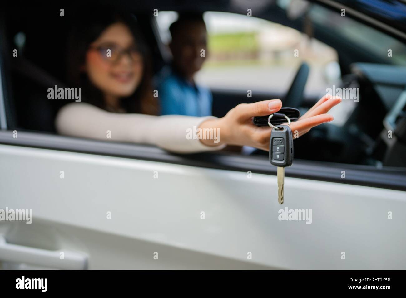 A young woman is handing over the car keys to someone from the drivers ...