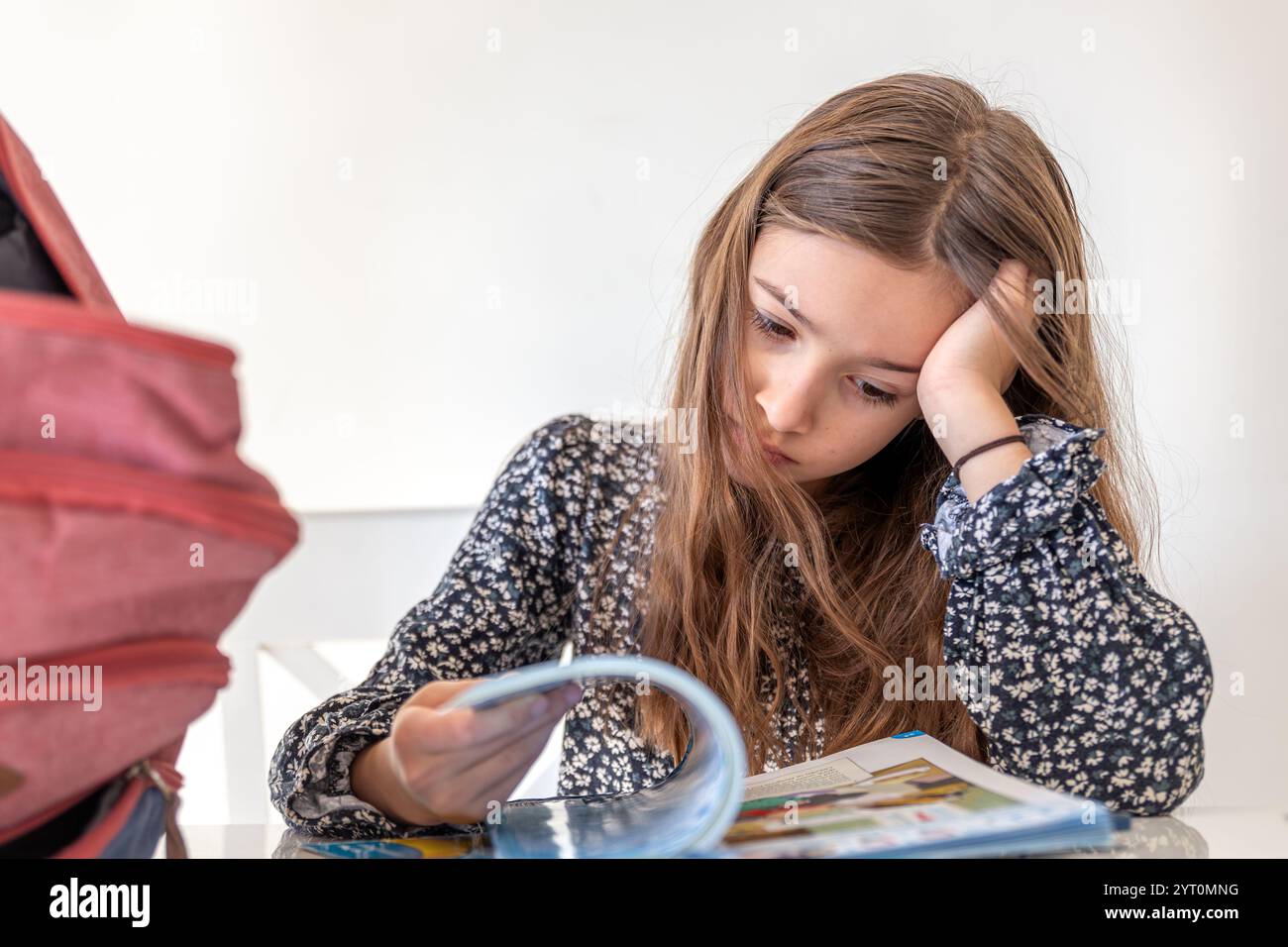 Sad girl reading a book at home. Girl student teaches lessons to school ...