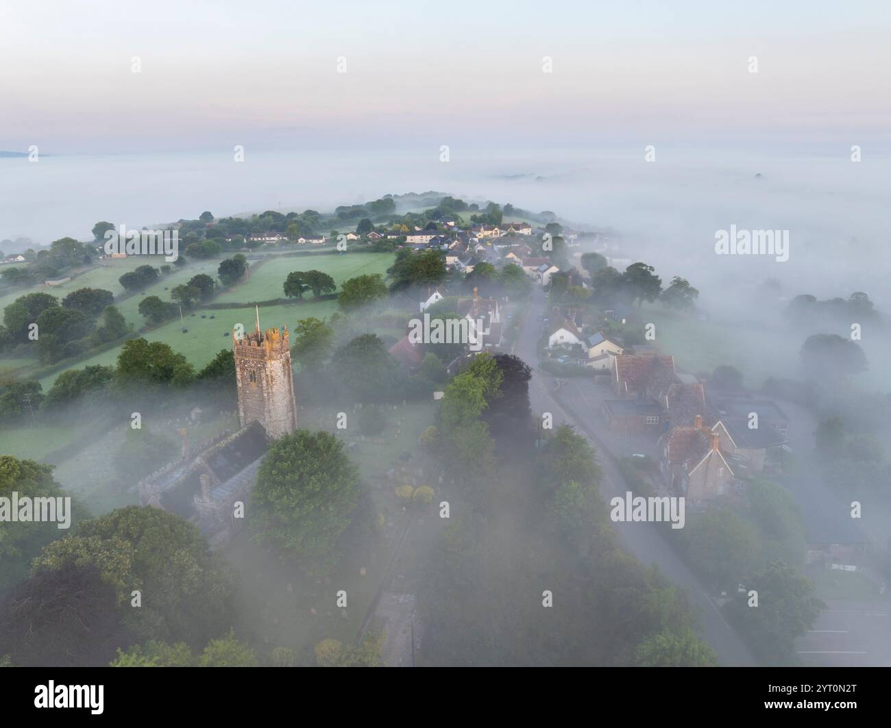 St Mary's Church and village emerging from morning mist at sunrise ...