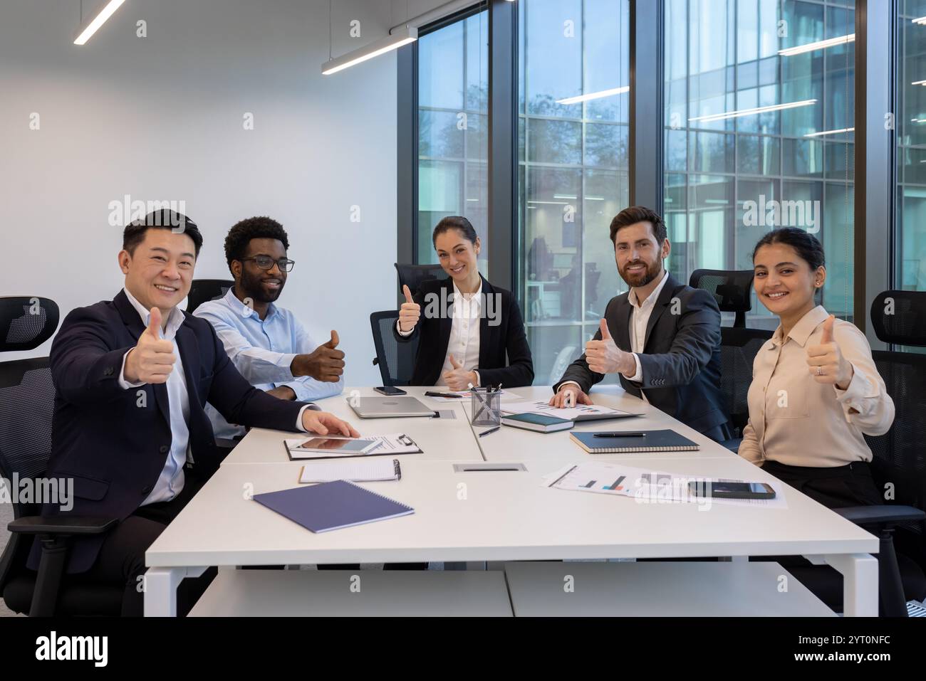 A diverse group of professionals sits around a conference table, giving ...