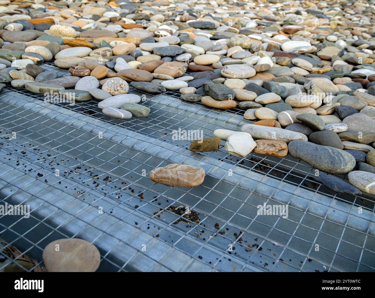 Decorating a roof made of corrugated sheets with sea pebbles laid on a ...