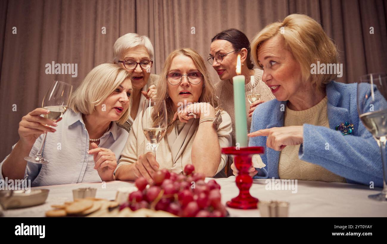 Elderly people, cheerful friends gathering at home in warmly-lit living ...