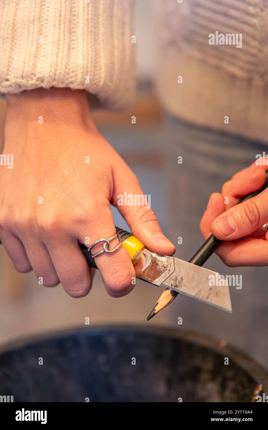 Woman artist sharpens pencil for drawing. Hands close-up sharpening a ...
