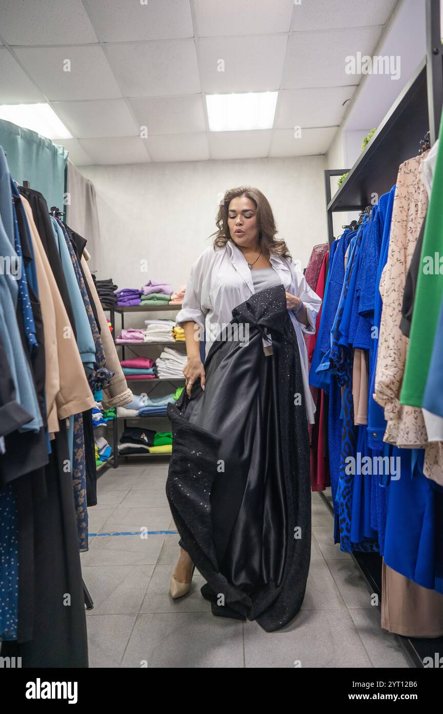 A fat woman chooses clothes in a plus size store. Vertical photo Stock ...