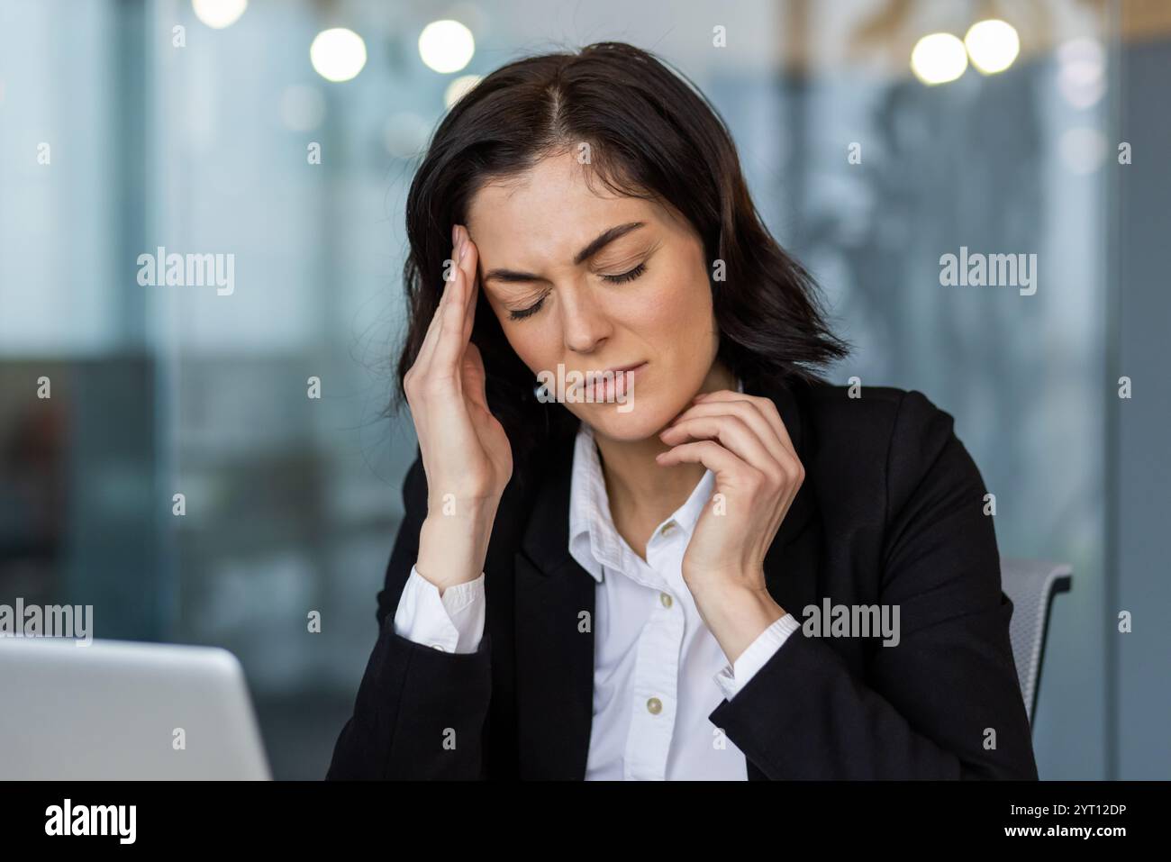 Businesswoman in office feeling stressed, holding head in hands ...