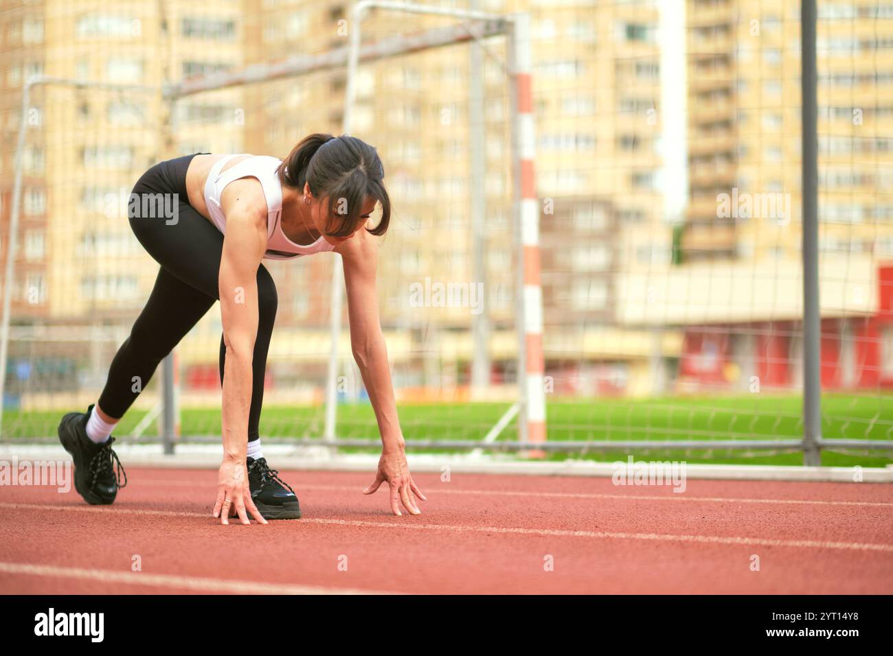 The athletic woman positions herself at the starting line, her focus ...