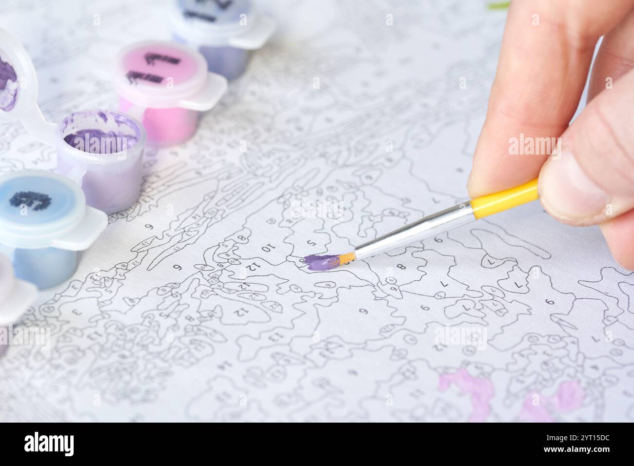 Hand painting by numbers with small brush and purple paint for ...