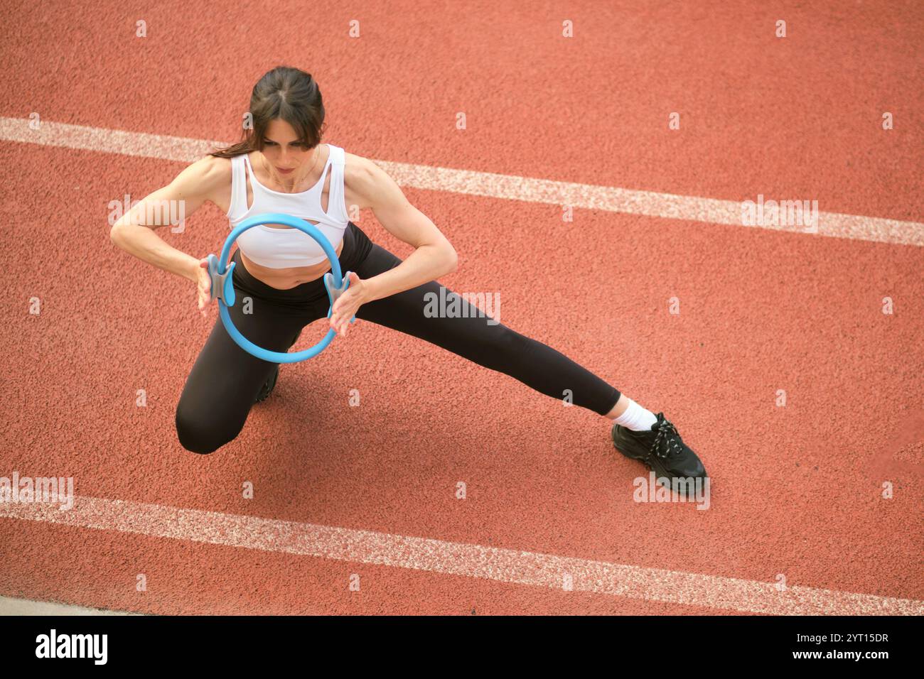 A fit woman performs a stretching exercise with a pilates ring on the ...