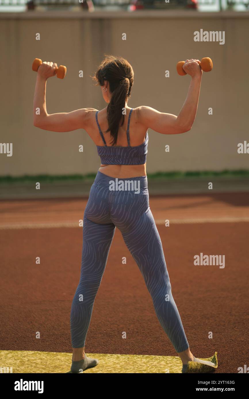 a yellow mat, the woman in blue sports attire performs a lunge with ...