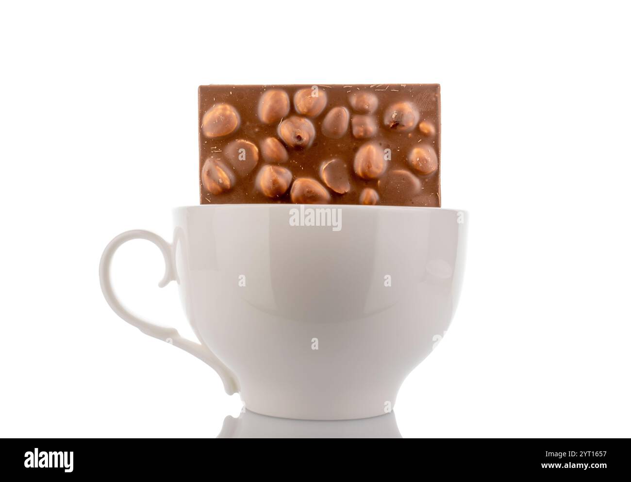 One bar of dark chocolate with hazelnuts in a ceramic dish, close-up ...