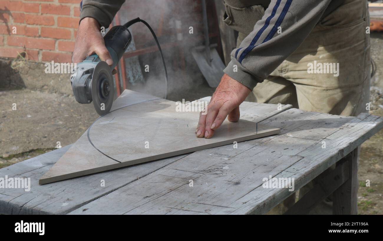 craftsman sawing off the contour of a rounded edge of a large stone ...