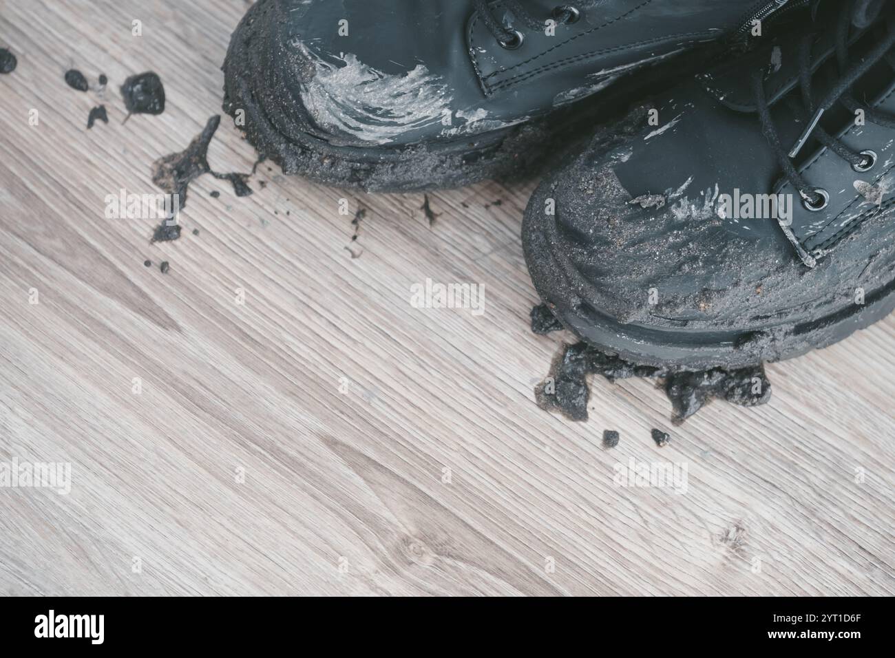 Muddy black boots and muddy footprints on a wooden floor, leaving a ...