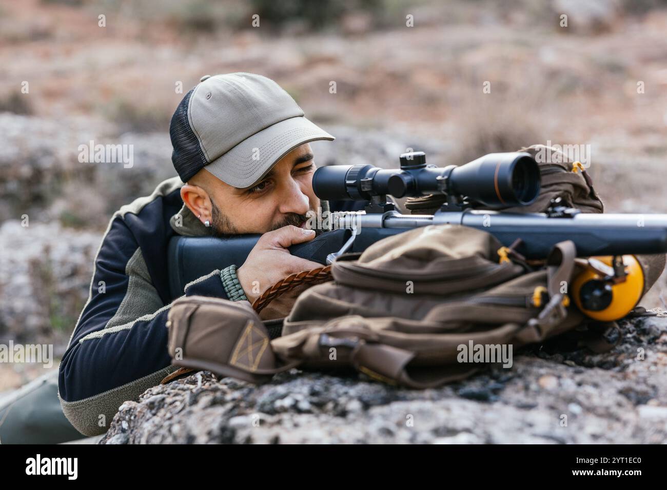 Hunter aiming with rifle lying on rocks in the mountain Stock Photo - Alamy