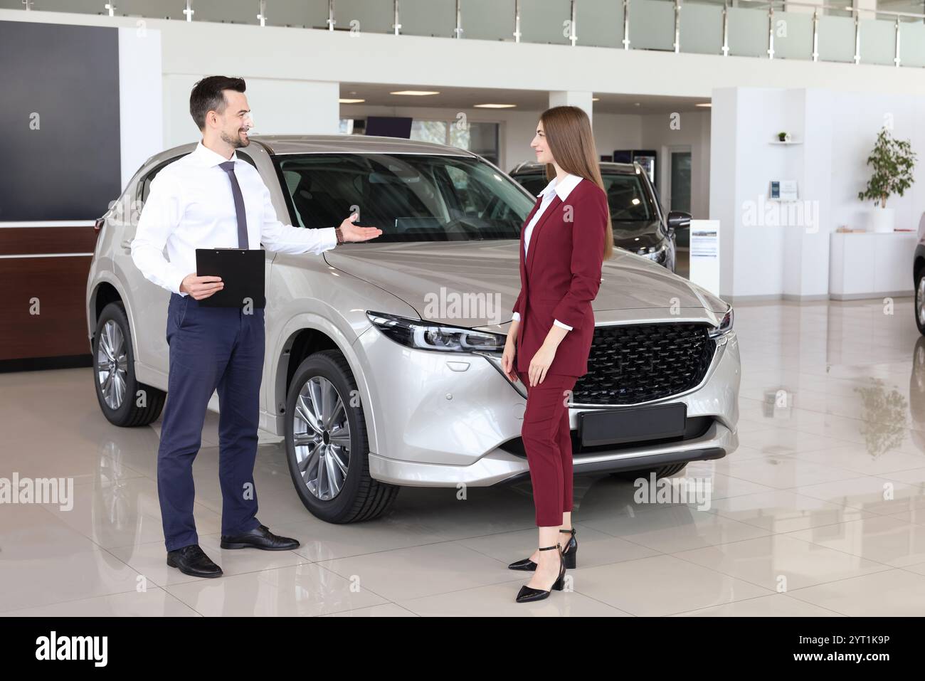 Salesman and client near new car in salon Stock Photo - Alamy