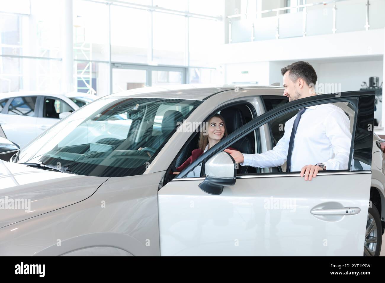 Happy salesman showing car to client in salon Stock Photo - Alamy