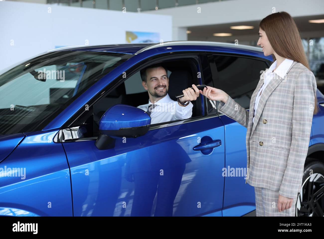 Saleswoman giving key to client inside new car in salon Stock Photo - Alamy