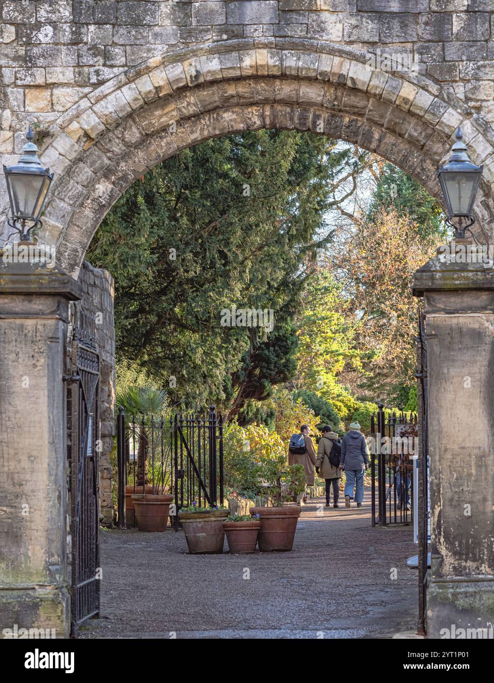 The arched entrance to a public park. Wrought iron gates open to a path ...