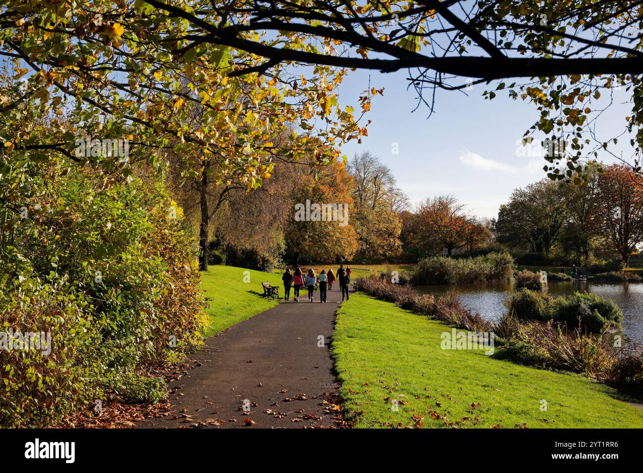 Group of people walking along a park path by water, Bury, England Stock ...