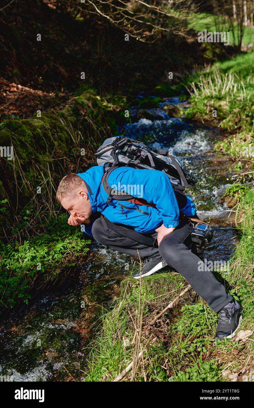 Hiker drinking stream water in mountain. Adult man drinking water from ...