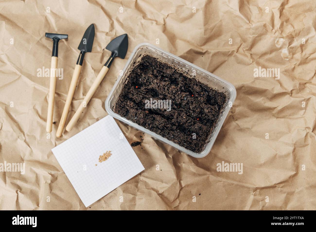Kraft paper background, fertile soil and garden tools on top, top view ...